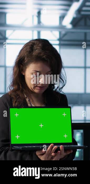 Vertical video Data center IT team automating routine maintenance tasks with green screen laptop ...