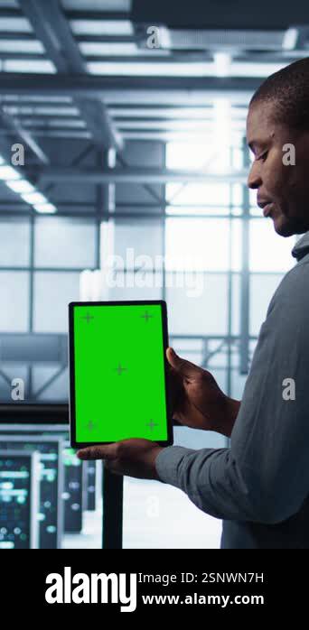 Vertical video Server room data scientists using mockup tablet, conducting security audits to ...