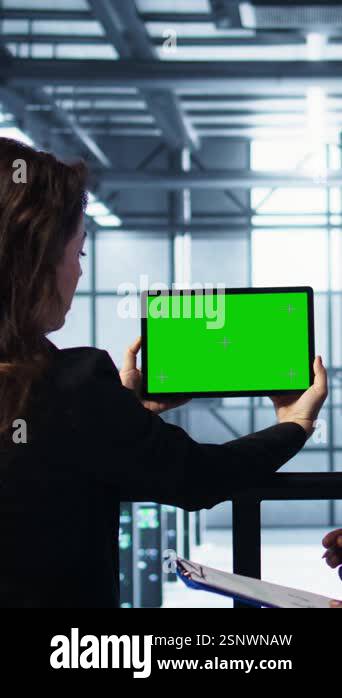 Vertical video System administrators in server farm using isolated screen mockup tablet to ...