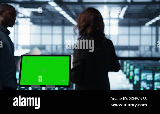 Close up of chroma key tablet next to server room data scientists conducting security audits ...