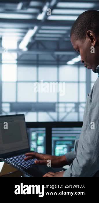 Vertical video Engineer in data center operating notebook, deploying ...