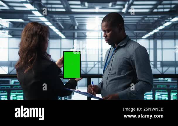 Engineers using green screen tablet in data center, checking ...