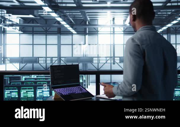 Technician in data center using AI on laptop and tablet, developing disaster recovery plans ...