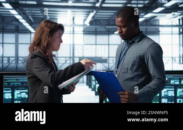 Data center team examines paperwork files in server room, reviewing ...