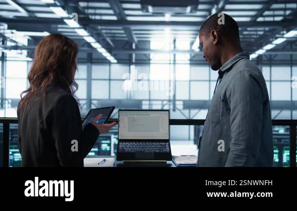 Programmers using AI technology on laptop and tablet in data center employing machine learning ...