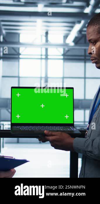 Vertical video Engineering team in data center using green screen laptop, implementing ...