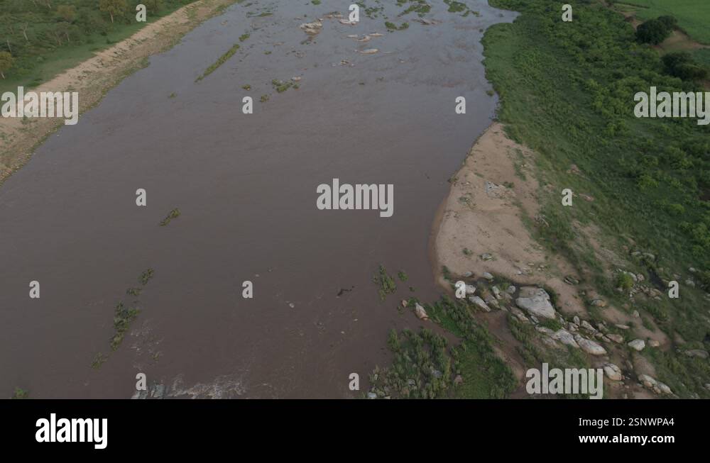 Cinematic aerial downward tilt of a flowing seasonal river that's ...
