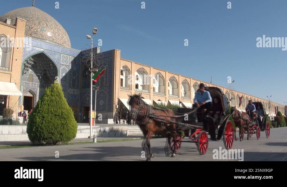 Tourists ride horse carts across the impressive Imam square in Isfahan ...