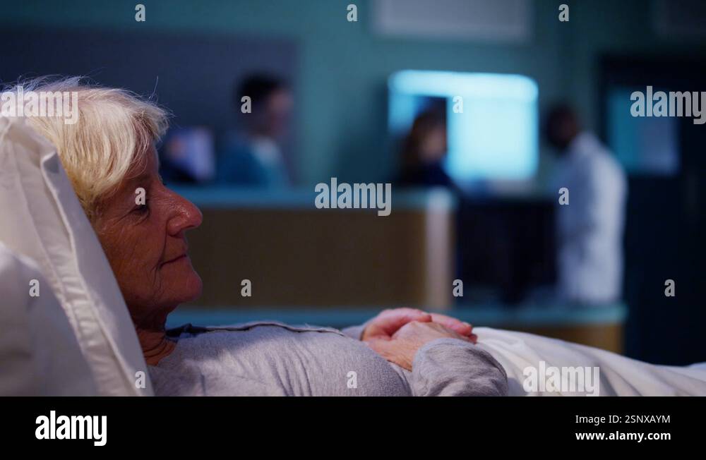 Elderly female patient resting in bed with medical team working in the ...