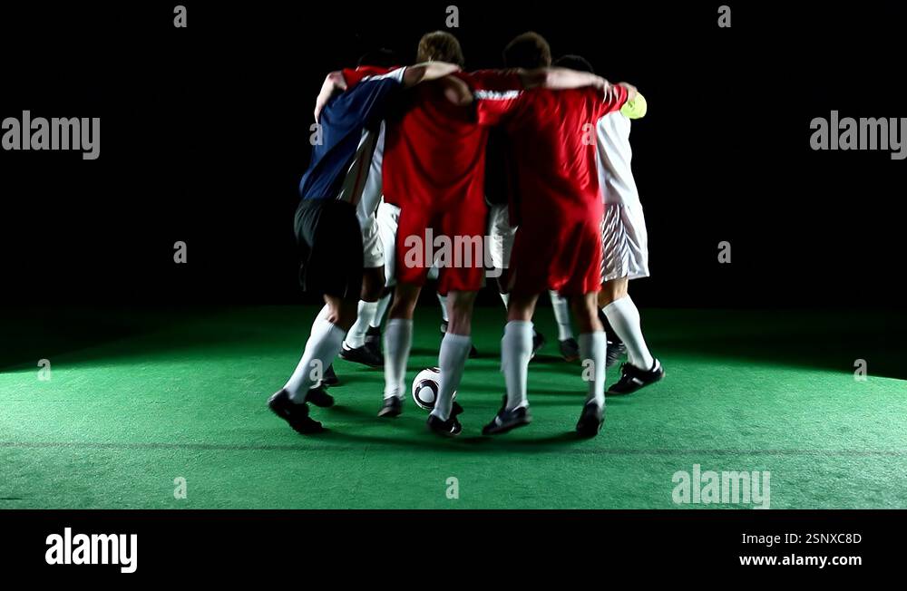 A group of soccer players huddle in a circle and jump together in ...
