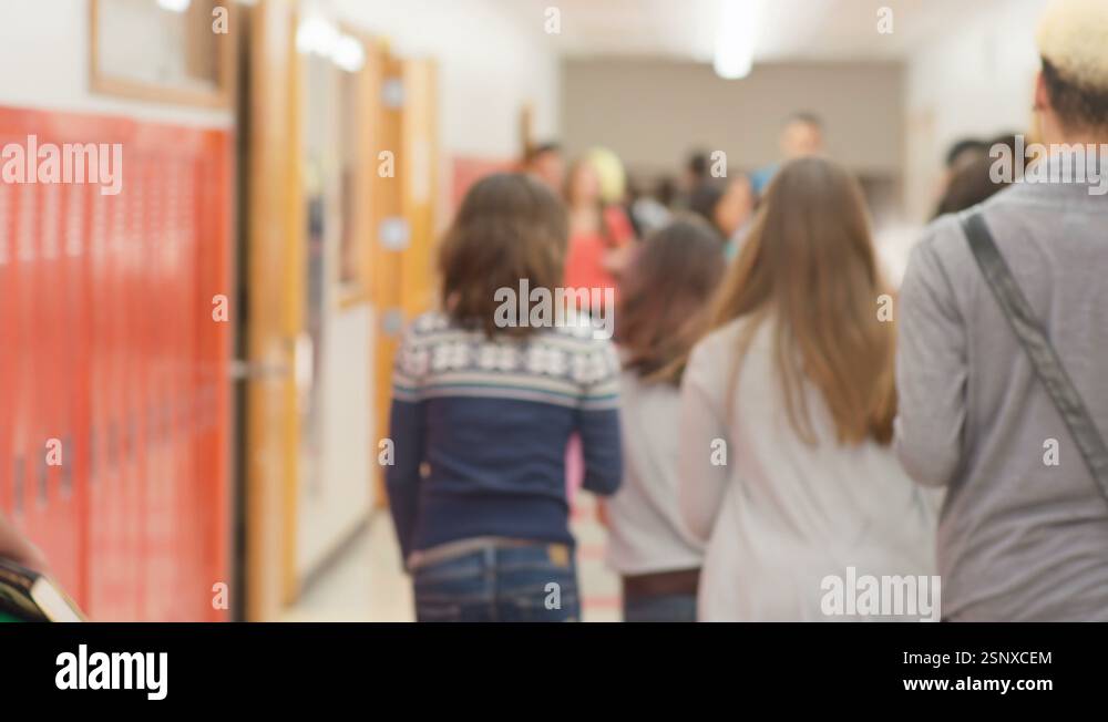 Students in a crowded hallway walk away in a hurry to their next class ...