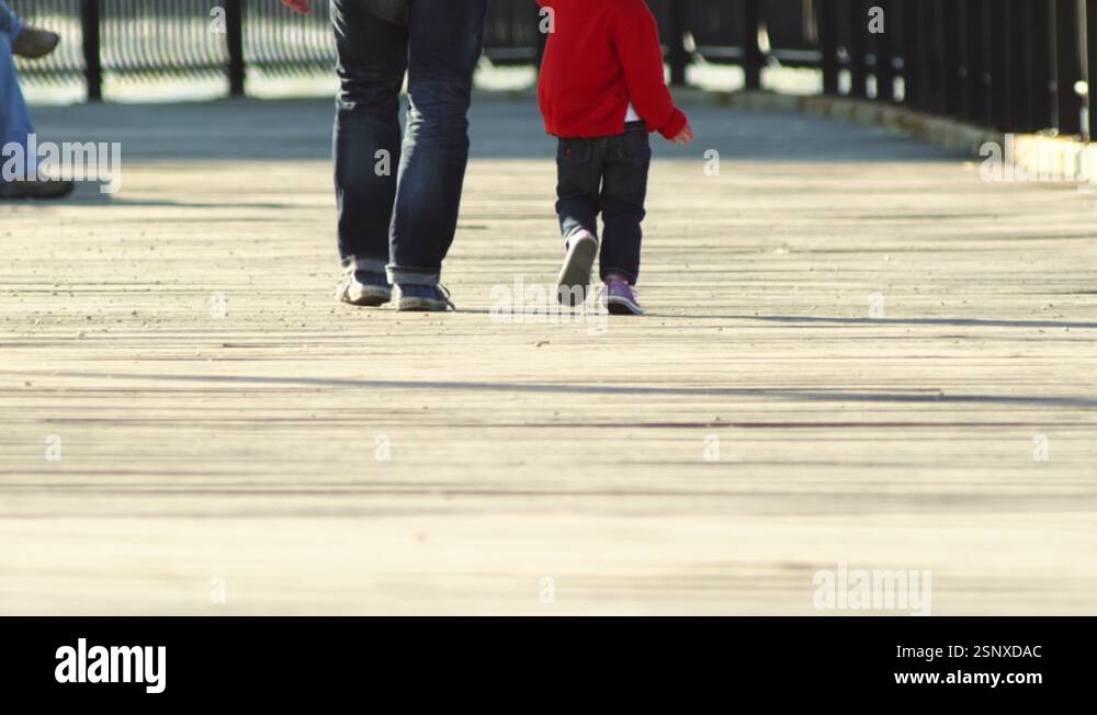 A little girl and her dad take a stroll down a boardwalk in New York ...