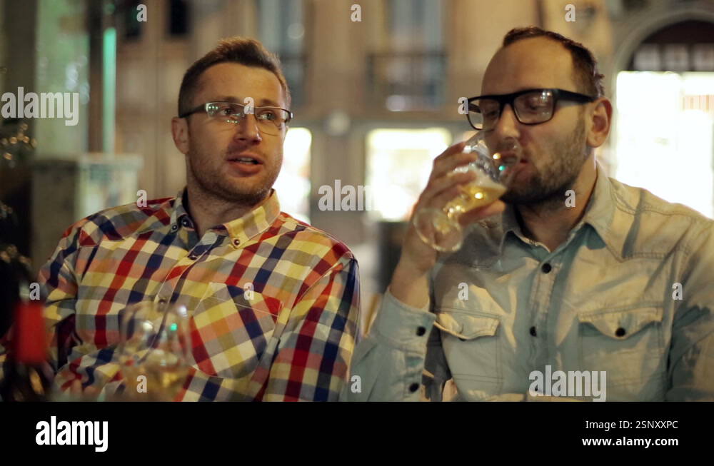 Two guys drinking beer and talking in the restaurant at night ...