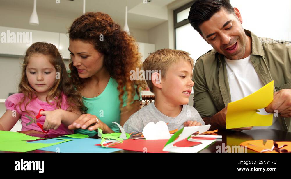 Happy parents and children doing arts and crafts at kitchen table Stock ...