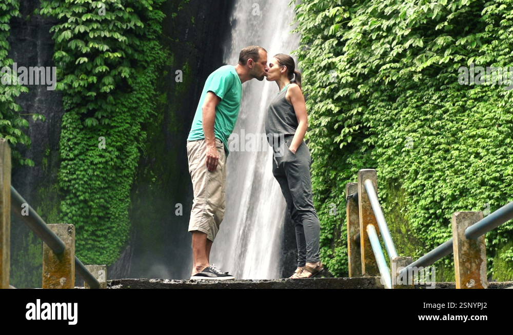 young couple kissing by beautiful waterfall In Bali, super slow motion ...
