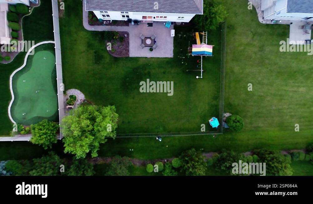 Aerial view of backyard putting green from in air flight above ground ...