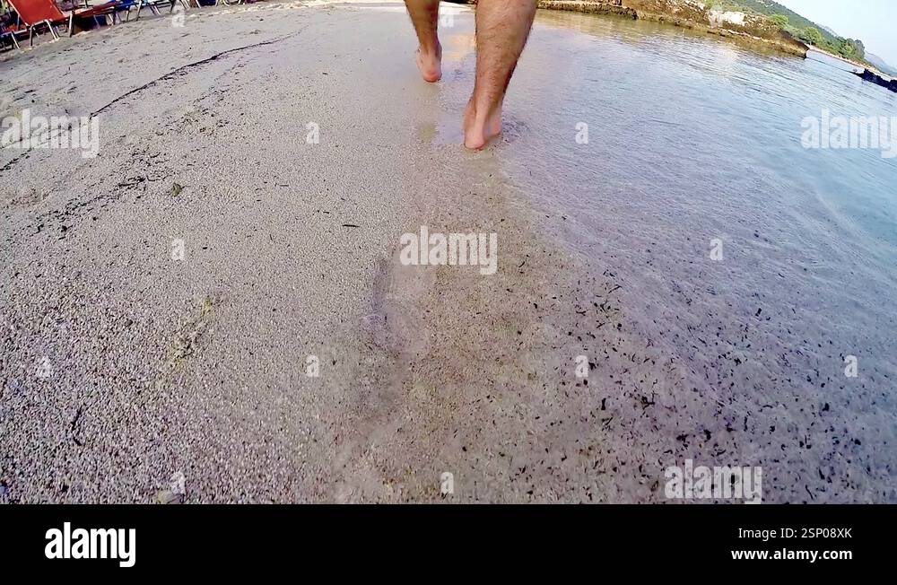 legs feet hispanic walking barefoot on wet sand island beach, back view ...