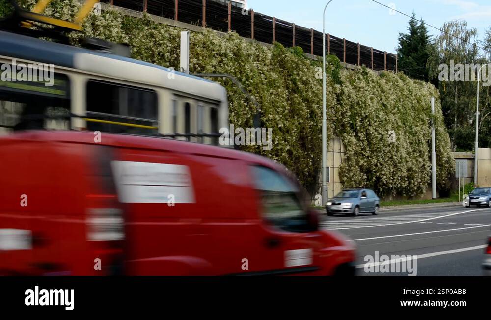 noisy urban street with passing cars and trams - noise barrier with ...
