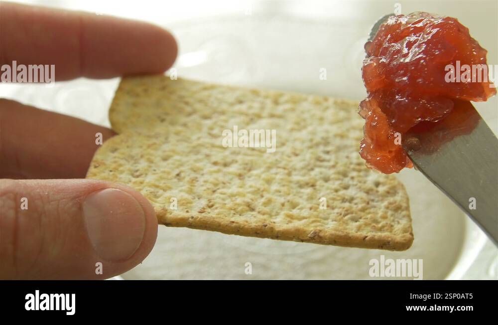 Spreading Jam on a whole wheat cracker for breakfast with a knife ...