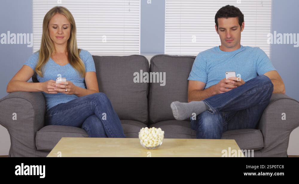 Couple texting on couch Stock Video Footage - Alamy