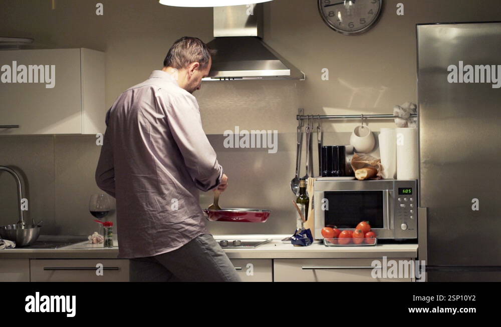 Young man cooking and adding seasoning in kitchen at home HD Stock ...