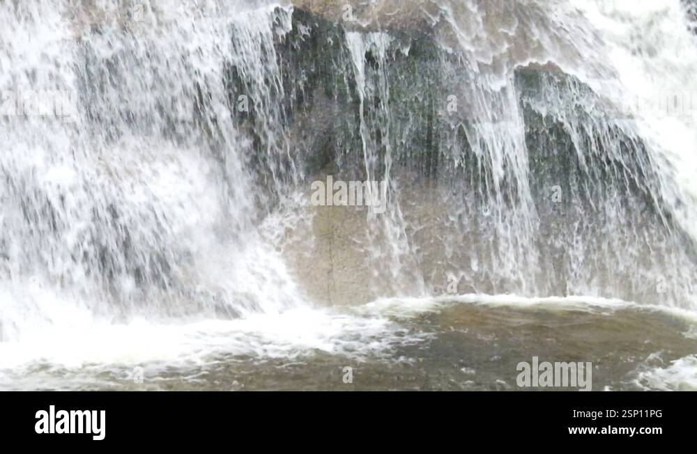 Winter view over snowy boulders to cascade of waterfall. Wavy water ...