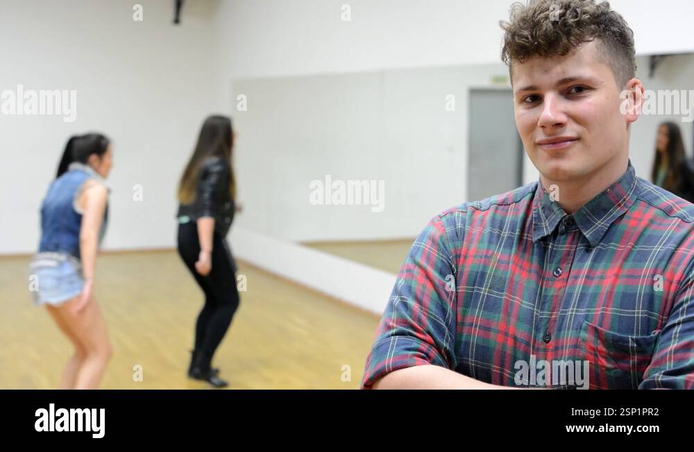 handsome man (dancer) smiles to camera - two woman dancing in ...