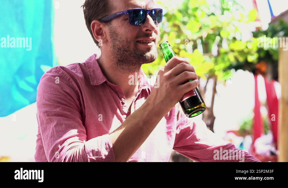 Happy man drinking cold beer in beach bar HD Stock Video Footage - Alamy