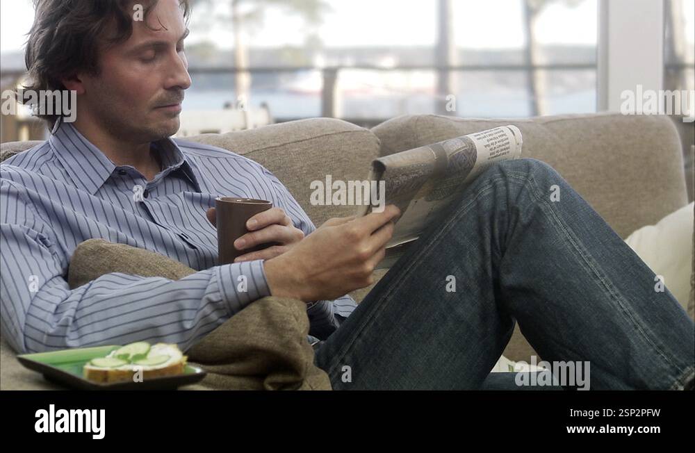 MS PAN Man sitting on sofa reading newspaper and drinking coffee ...