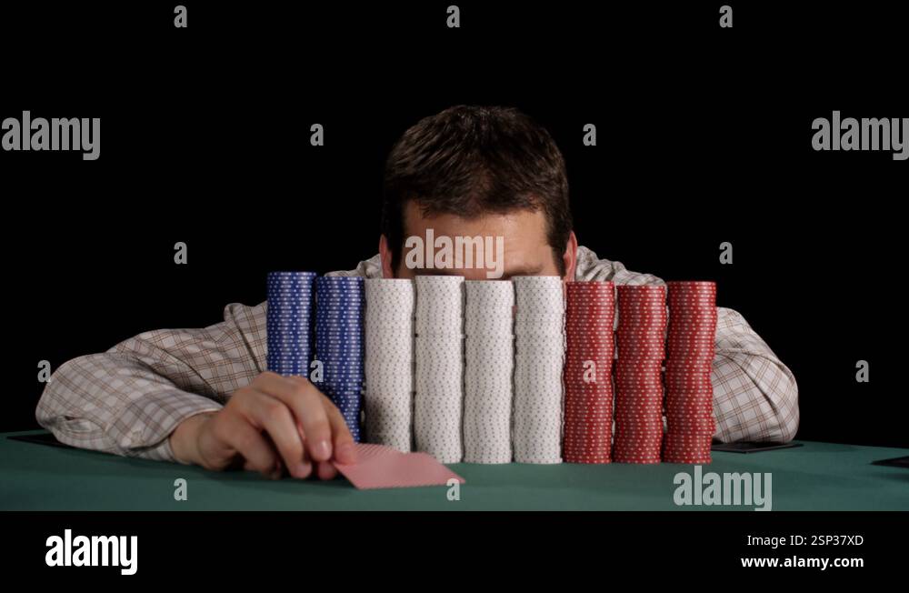 Poker player pops up from behind his stacks of chips, looks at cards ...