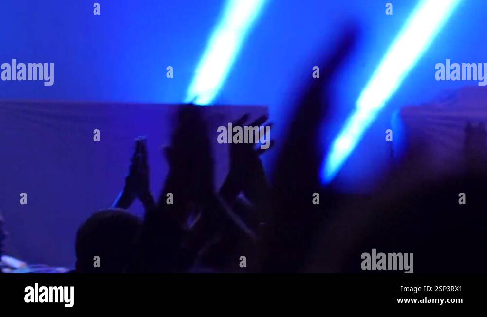 Cheering crowd fans audience in lumiere light on a concert clapping ...