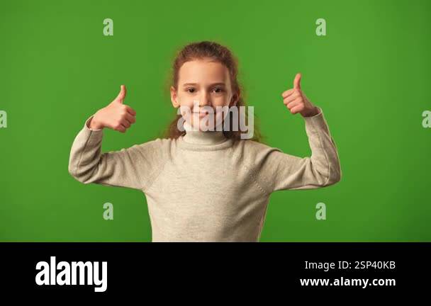 Children emotions concept. Little girl child looks at camera and shows thumbs up hand signs ...
