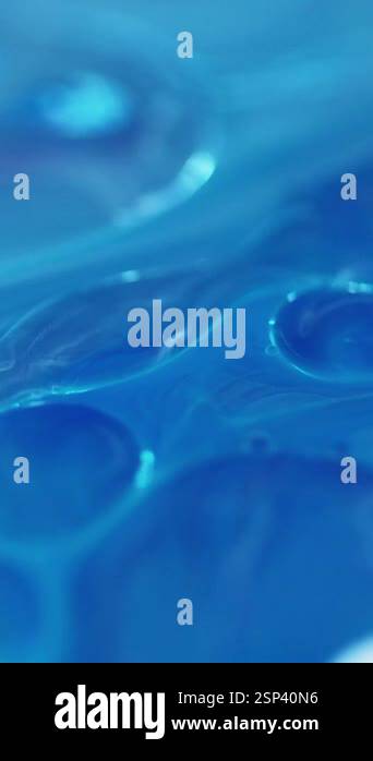 Vertical video. Oil bubbles. Fizzy liquid. Defocused blue white color ...