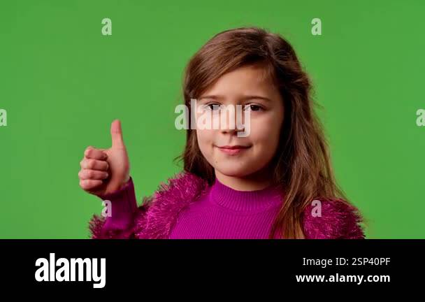 Children emotions concept. Smiling girl child looks at camera and shows thumb up hand sign ...