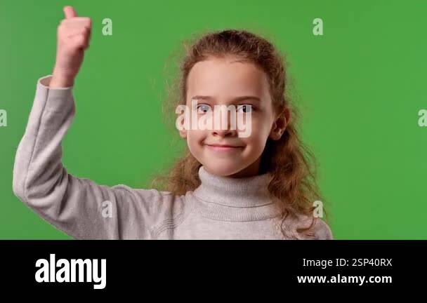 Children emotions concept. Little girl child looks at camera and shows thumb up hand sign ...