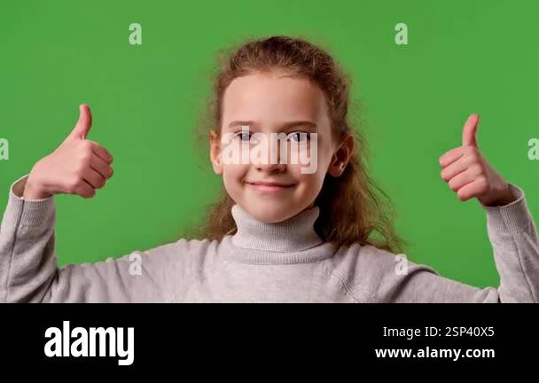 Children emotions concept. Little girl child looks at camera and shows thumbs up hand signs ...