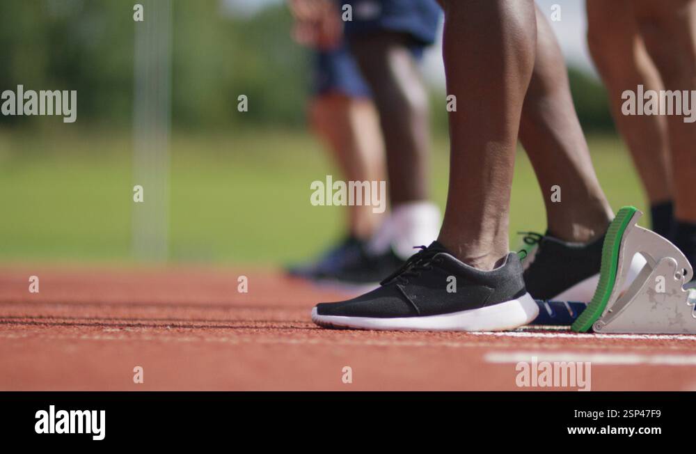 4K Group of athletes at running track, crouch at starting line before a ...