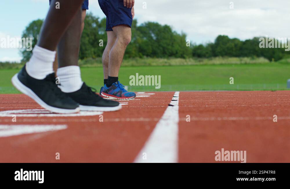 4K Group of athletes at running track, crouch at starting line before a ...
