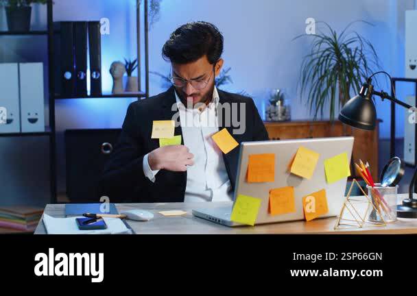 Tired exhausted Indian businessman working on laptop at office with ...