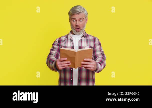 Mature man opens book with eager hope, showing bright surprise and ...