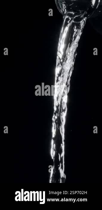 Pure water is being poured out from a glass bottle on black background ...