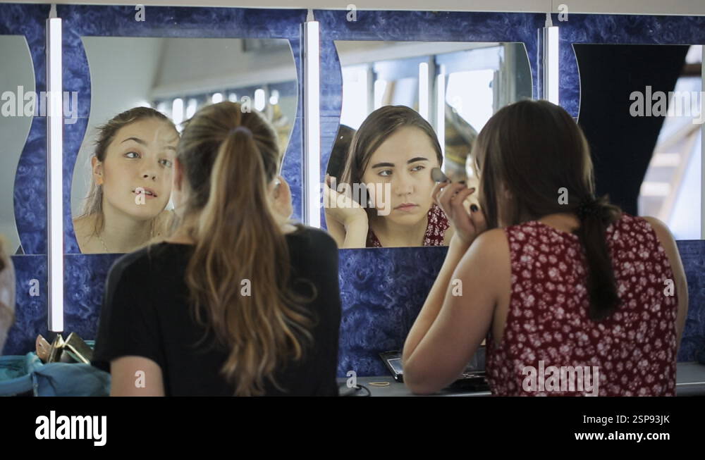 Two girls sit in front of mirror and are busy with smartening up Stock ...