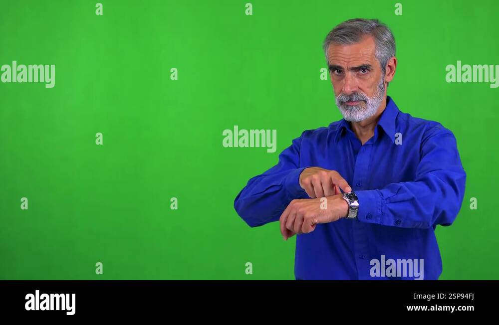 old senior man points on watch (show time) - green screen - studio ...