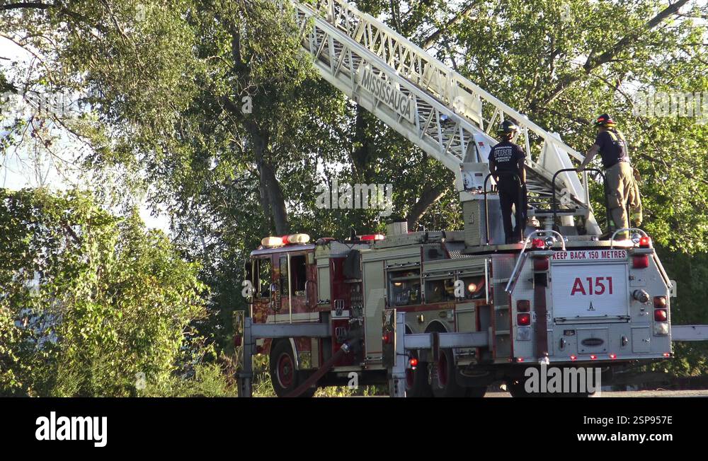 Two firemen on top of a fire truck with fire hose attached to a ladder ...
