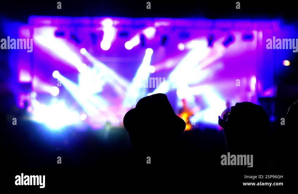 Lighting effects on a rock concert stage at night. Crowd's heads in the ...