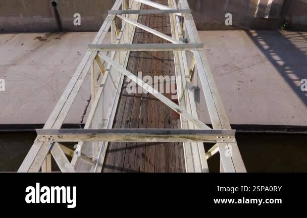 erial footage of a pedestrian bridge spanning over a drainage channel ...