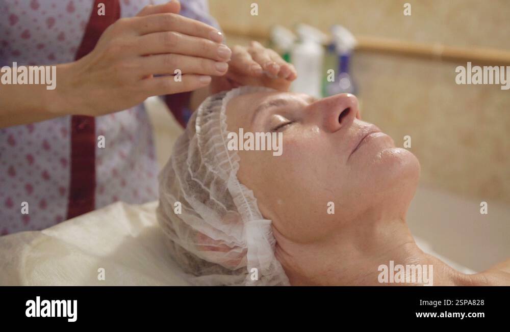 Woman middle-aged take face and neck lymphatic, drainage massage in spa ...