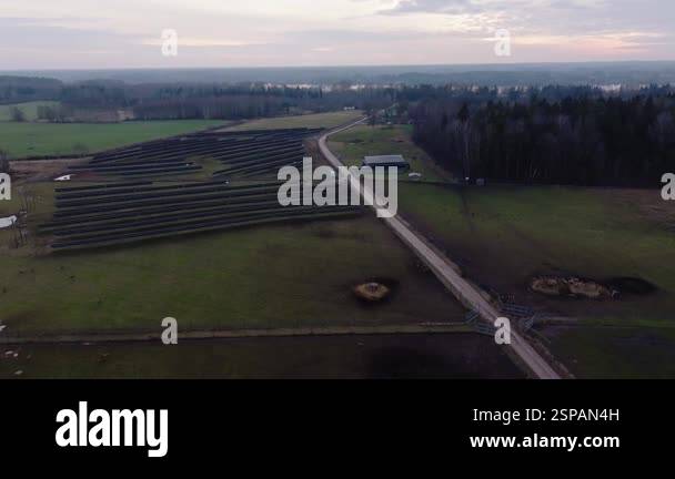 A large solar panel array spans open fields divided by a dirt road ...