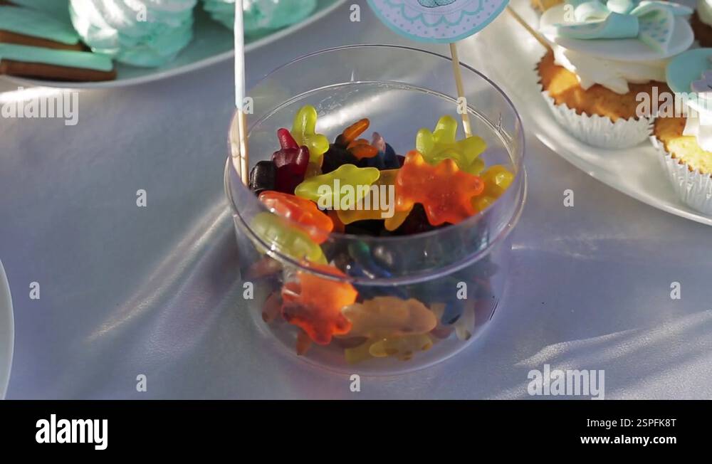 A lot of a gummy candy in a transparent box made of plastic or a glass ...