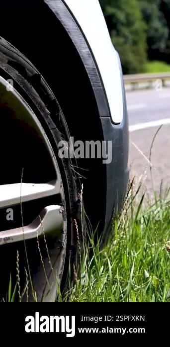 Vertical portrait footage of a car with a flat tyre after a large blow ...
